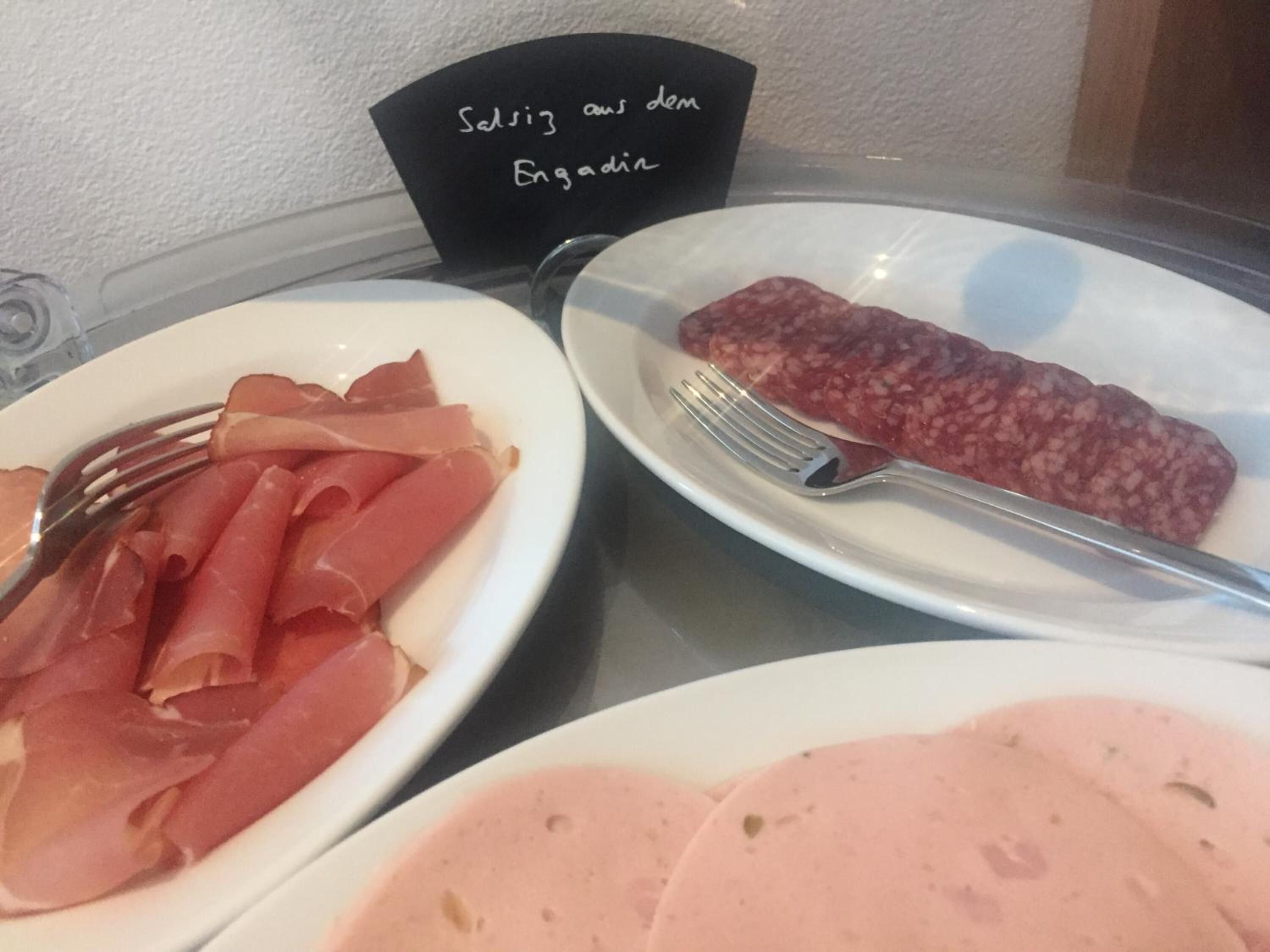 Uma mesa com pratos de carnes fatiadas e um letreiro.