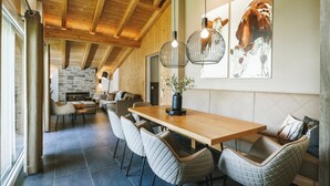 Uma sala de jantar com uma mesa de madeira e cadeiras estofadas, uma lareira de pedra e obras de arte na parede.