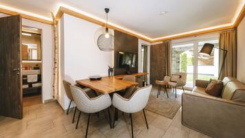 Uma sala de estar moderna com uma mesa de jantar de madeira, duas cadeiras, um sofá e uma TV.