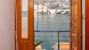 Uma porta de madeira que dá para uma varanda com vista para um lago e montanhas.