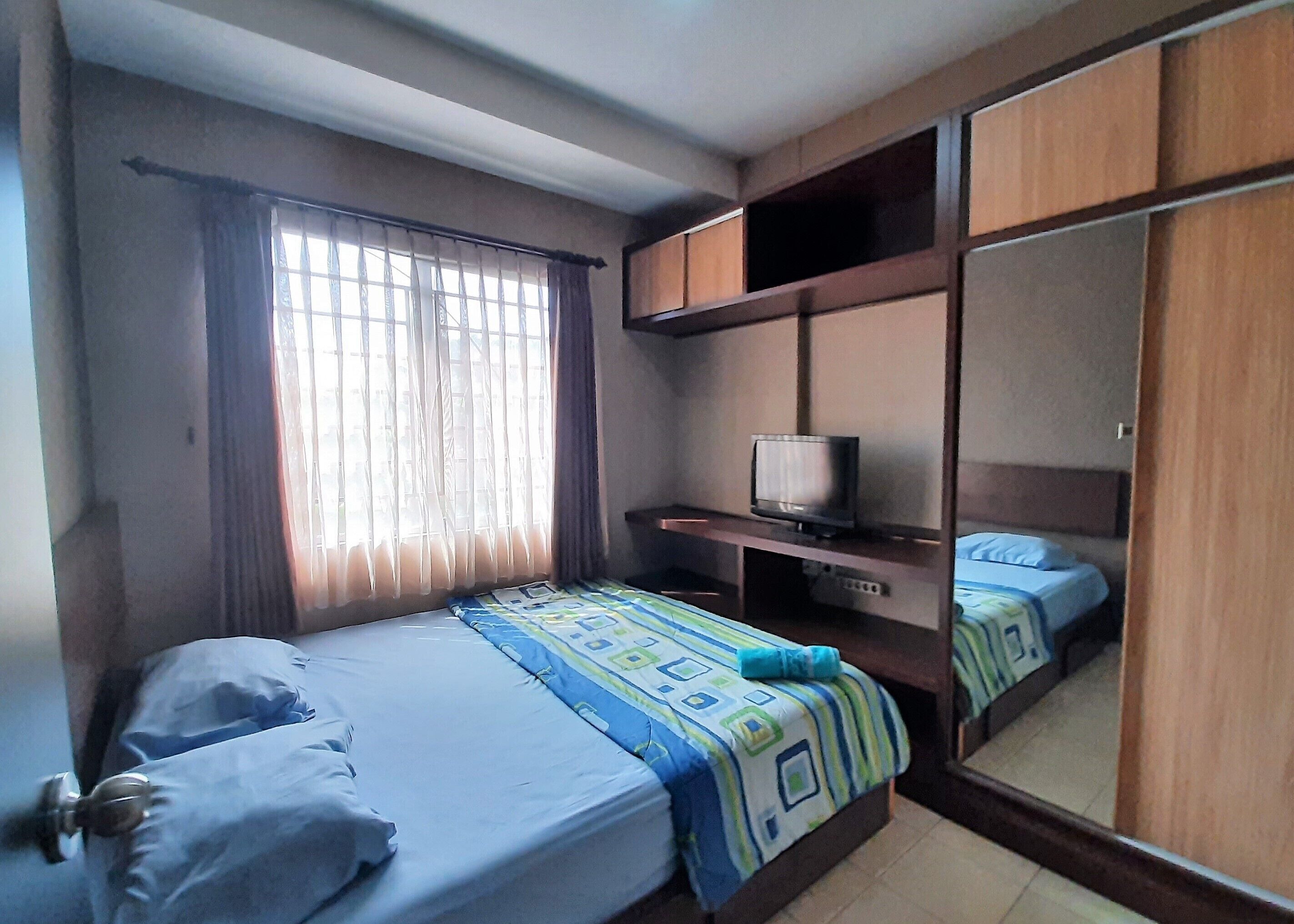Quarto com uma cama, uma televisão numa estante e um guarda-roupa.