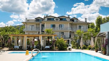 Um hotel com piscina, área de estar ao ar livre e um edifício grande com várias varandas.