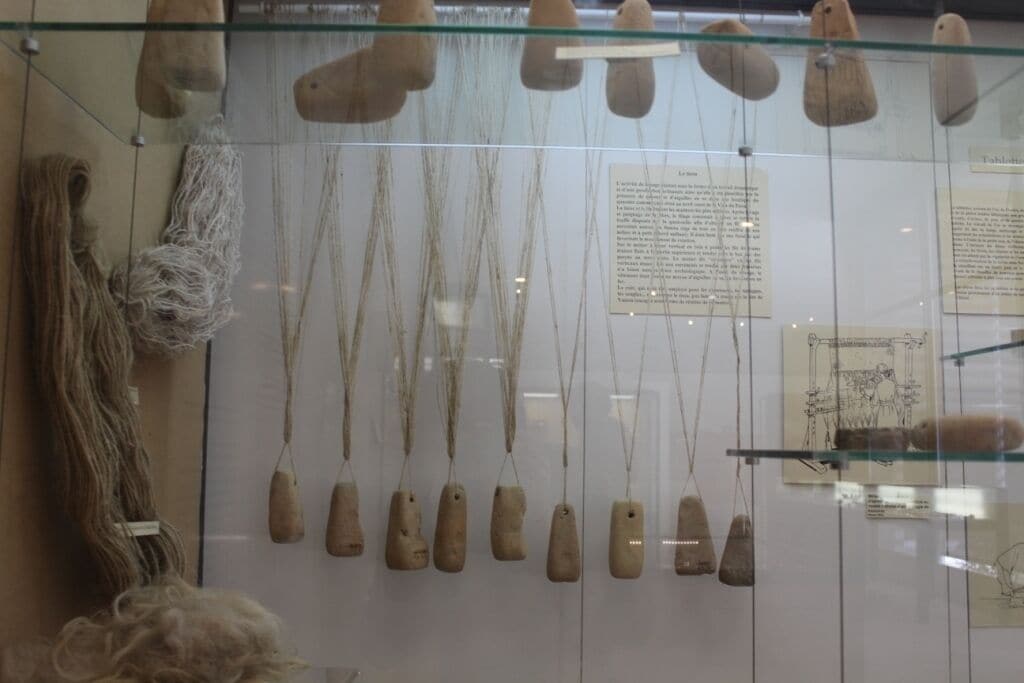 Exposição de vários objetos, incluindo peças penduradas e um grande novelo de corda, provavelmente em um museu ou galeria.