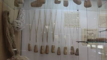 Exposição de vários objetos, incluindo peças penduradas e um grande novelo de corda, provavelmente em um museu ou galeria.