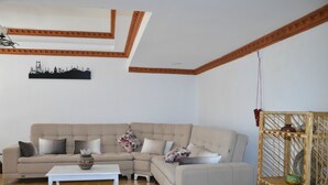 Uma sala de estar com um sofá modular bege, uma mesa de centro branca e um objeto decorativo na parede.
