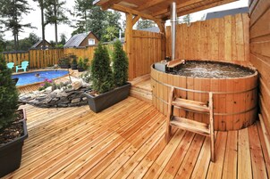 Um deck de madeira com hidromassagem, piscina e área de estar ao ar livre.