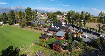 Zona residencial com casas, um campo verde e montanhas ao fundo.