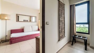 Quarto de hotel com cama, mesa de cabeceira, luminária, janela com vista e uma obra de arte na parede.