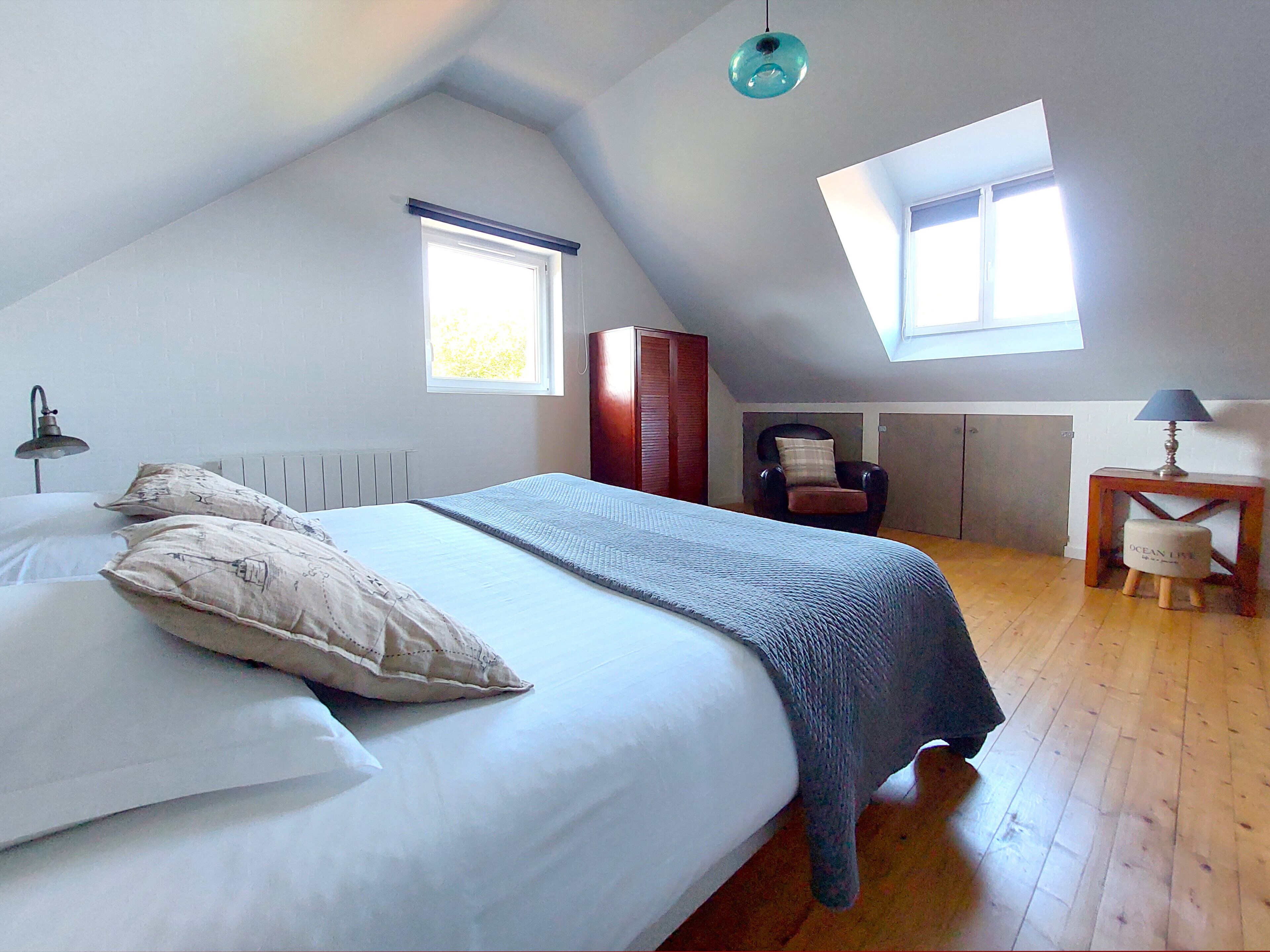 Quarto com cama, uma cadeira, uma mesa e uma janela.