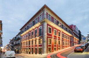 Um edifício vermelho com vários andares, janelas amplas e varandas.