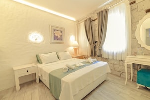 Quarto bem arrumado com cama, mesa de cabeceira, abajur e espelho.