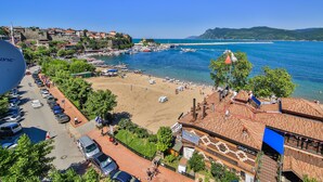 Uma vila costeira com praia, barcos e um edifício histórico com telhado de azulejos.