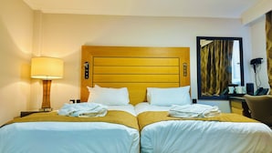 Quarto de hotel com cama de casal, mesa de cabeceira com abajur, secador de cabelo e espelho.
