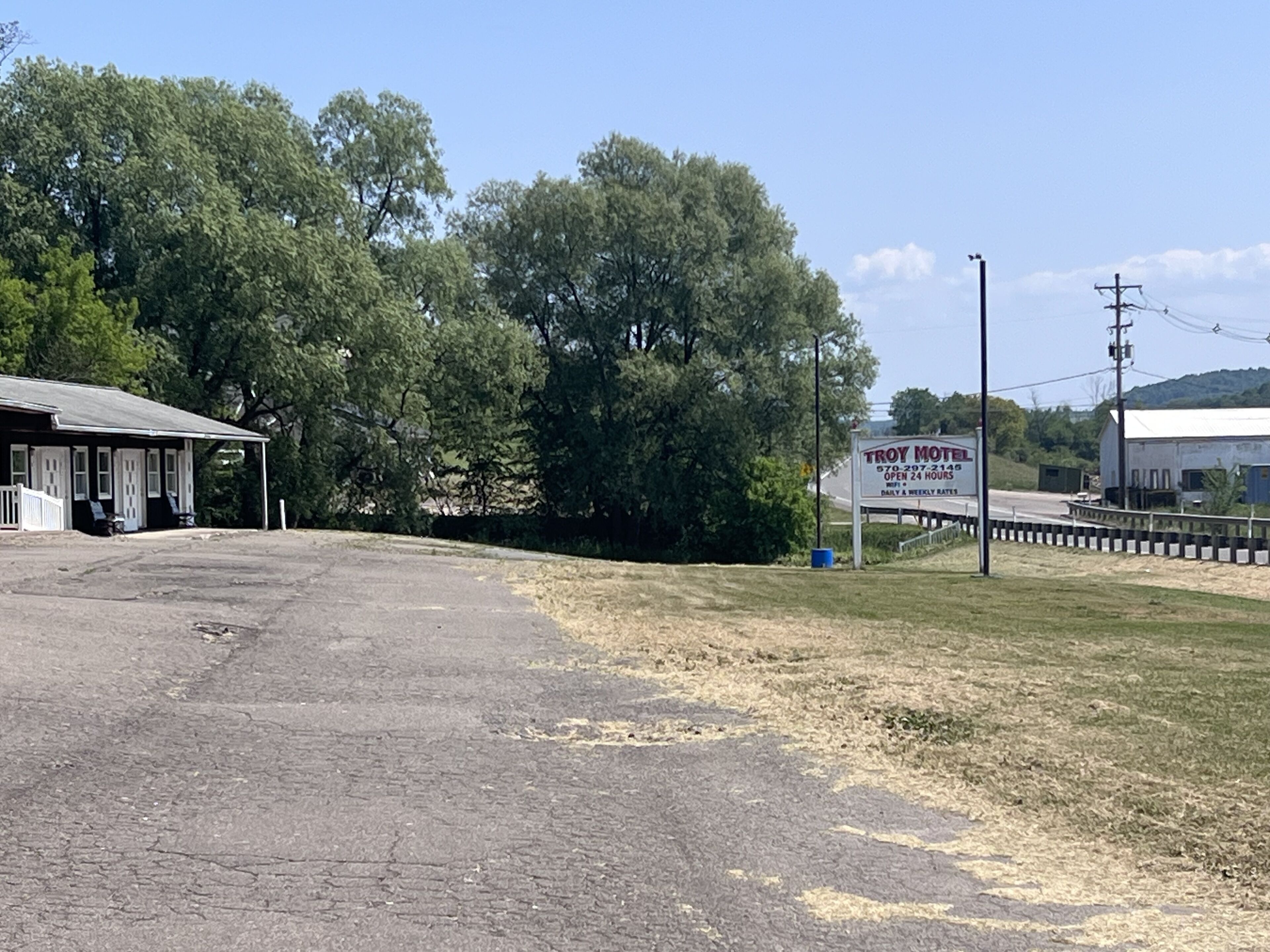 Um cenário rural com placa de motel, um pequeno edifício e uma área gramada.