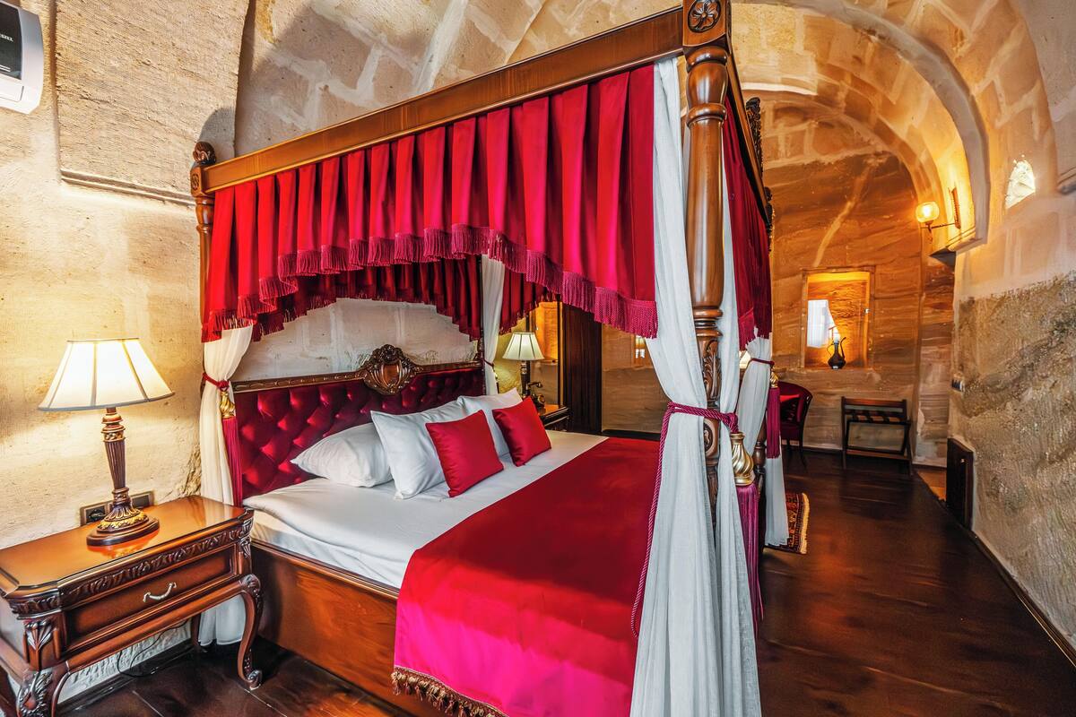 Um quarto luxuoso com cama de dossel, mesa de cabeceira e uma cadeira.