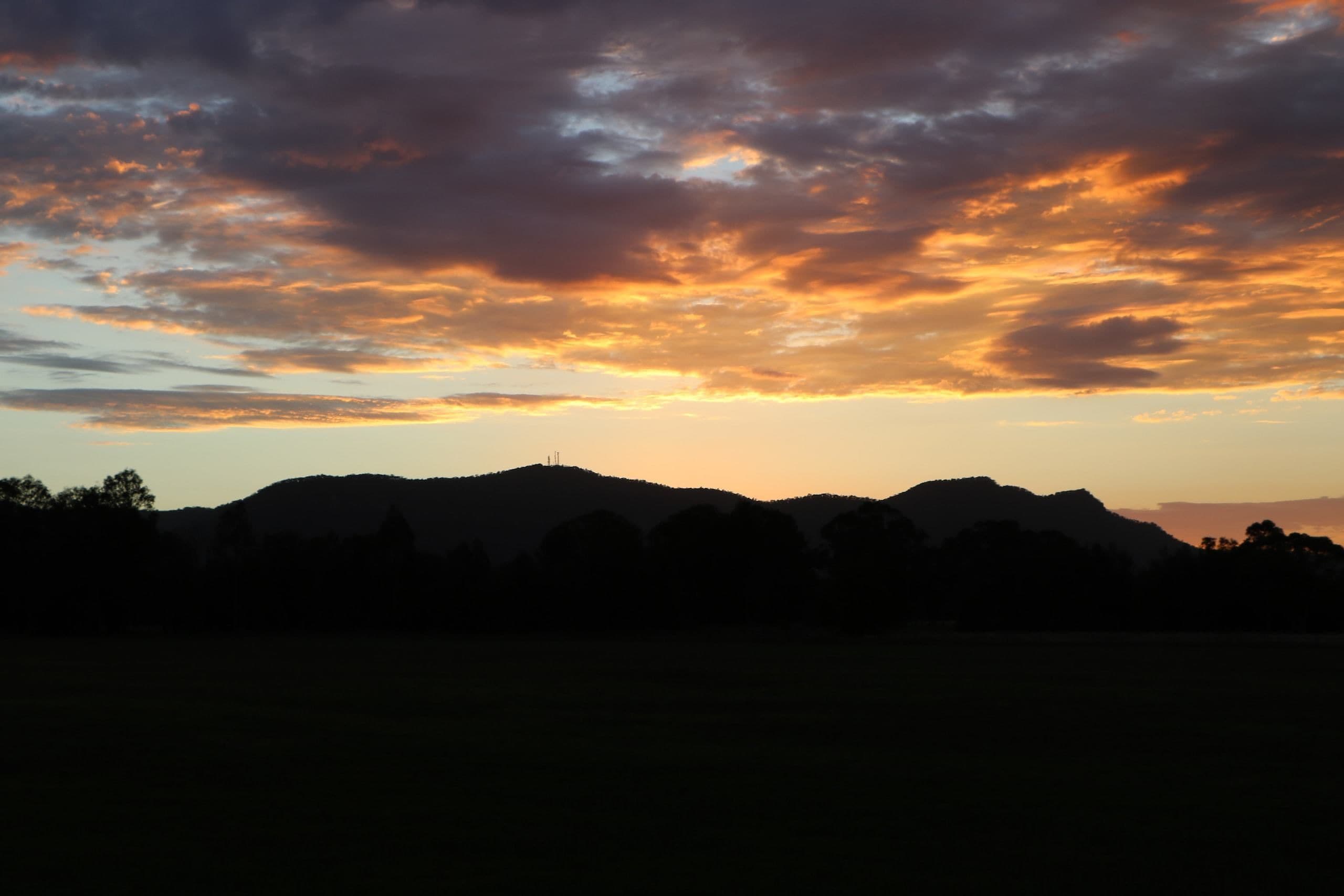 Silhueta de uma cordilheira contra um céu ao pôr do sol.
