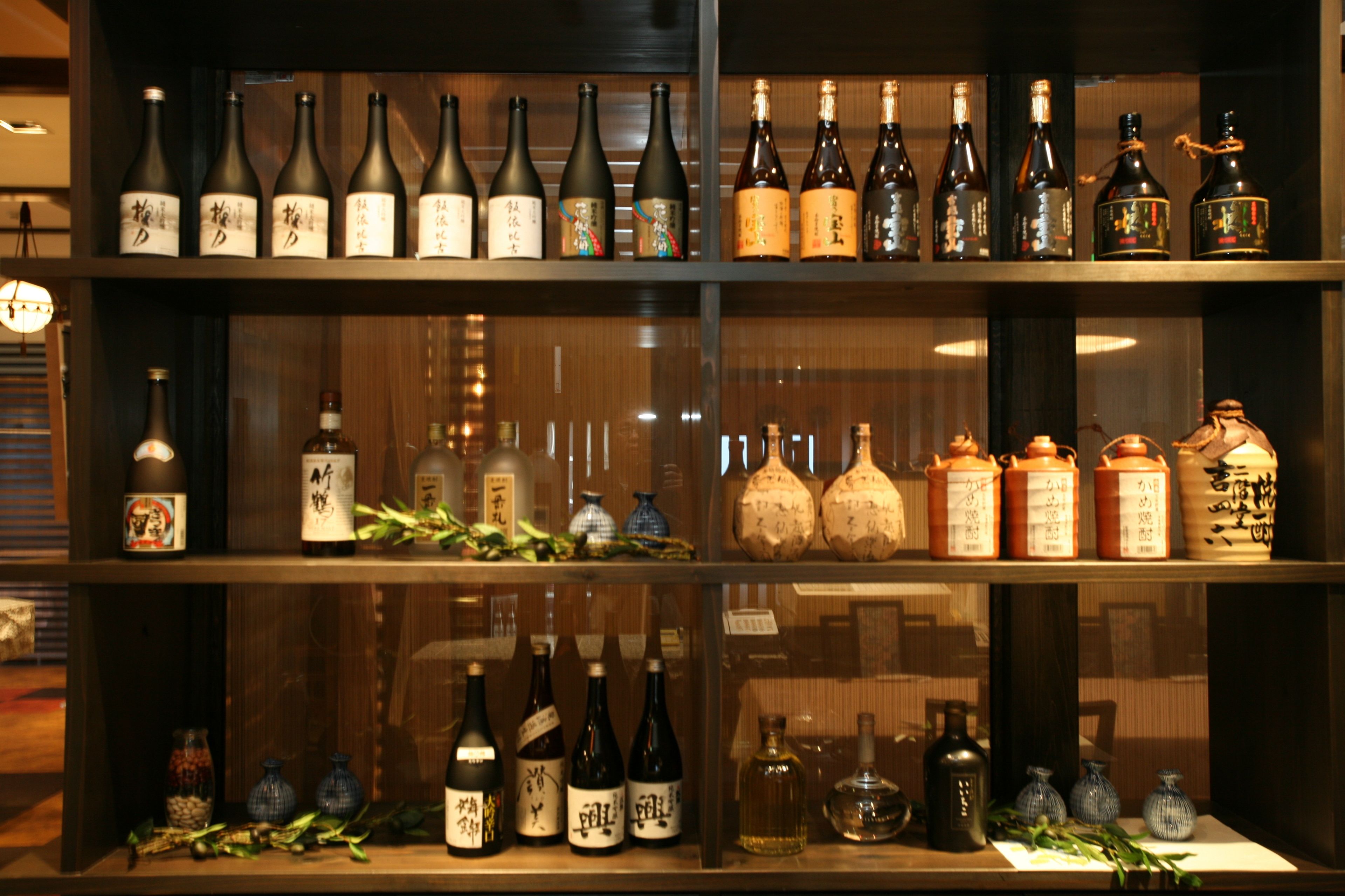 Exposição de diversos frascos e recipientes, provavelmente para bebidas, dispostos em prateleiras.