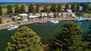 Uma marina com vários barcos atracados, rodeada por edifícios residenciais e vegetação exuberante.
