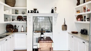 Uma cozinha com armários brancos, uma mesa de madeira e um fogão.