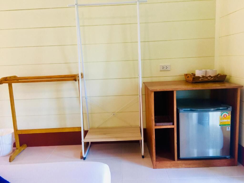 Quarto com estrutura de cama de madeira, escada de metal, pequena mesa de madeira e uma lixeira, além de uma tomada na parede.