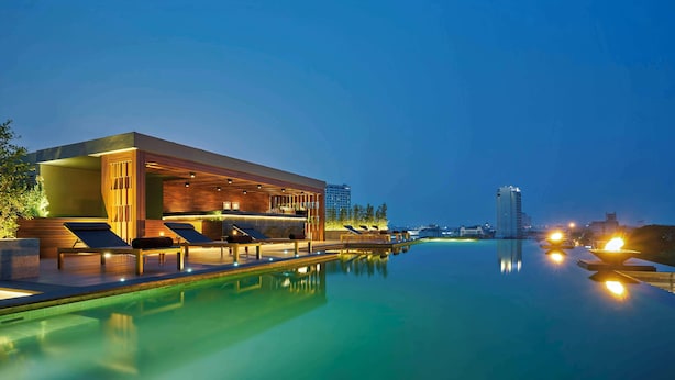 Um hotel moderno com piscina, espreguiçadeiras e um bar.