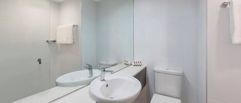 Casa de banho moderna com cabine de duche em vidro, lavatório branco e sanita.
