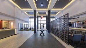 Um hall de hotel moderno com balcão de recepção, área de estar e bar.