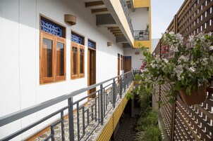 Um edifício com várias janelas, uma varanda com guarda-corpo e um vaso de flores pendurado.