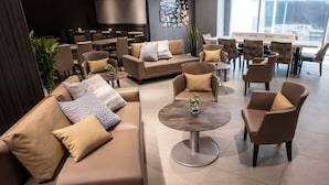 Uma área de estar moderna com sofás, poltronas e uma mesa redonda.