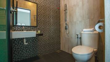 Um banheiro moderno com parede de azulejos hexagonais, pia branca e vaso sanitário com suporte para toalha de papel.