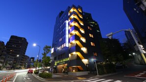 Um hotel moderno com fachada em zigue-zague, grandes janelas e entrada bem iluminada.