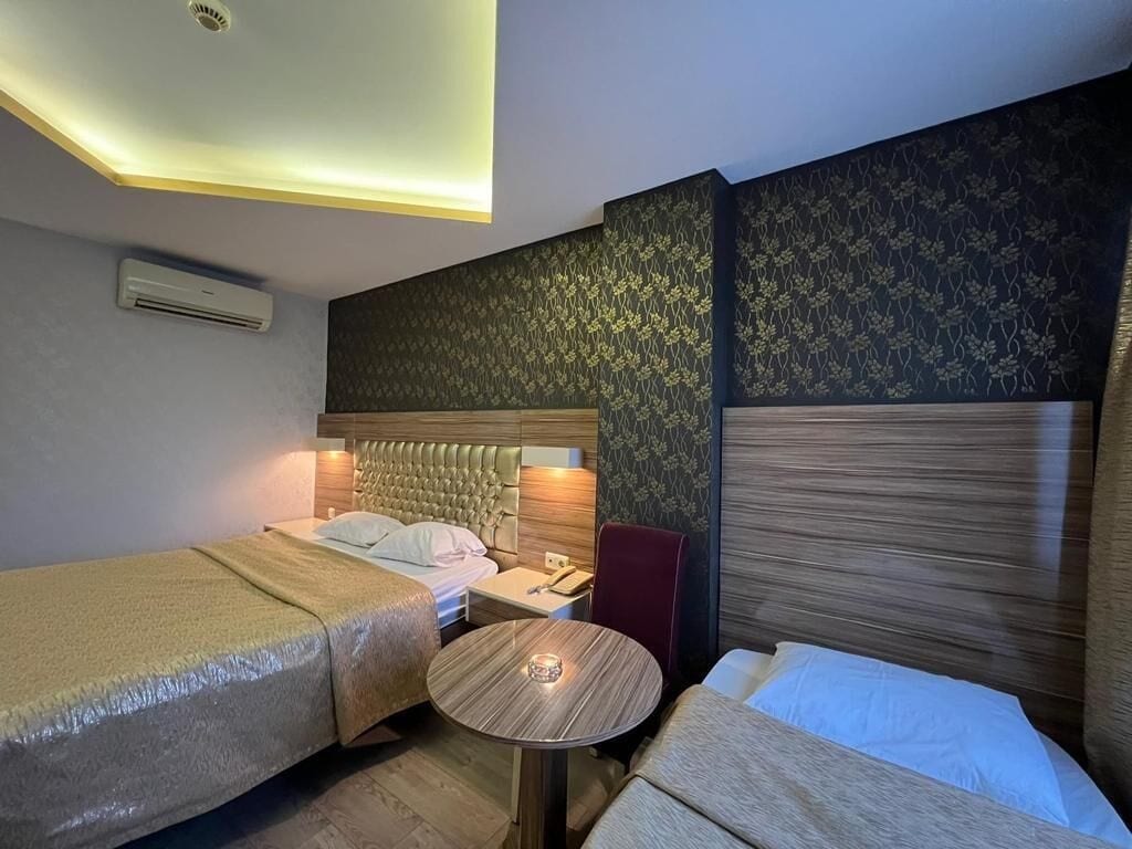 Quarto de hotel com duas camas de solteiro, uma mesa redonda e um pequeno espaço para sentar.