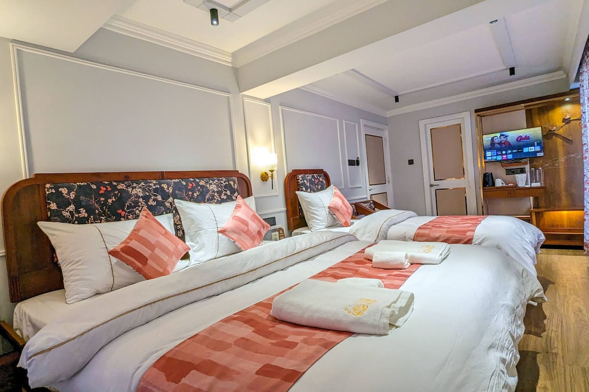 Quarto de hotel com uma cama grande, televisão e guarda-roupa de madeira.