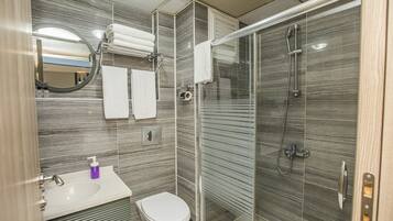 Casa de banho moderna com cabine de chuveiro em vidro, lavatório branco e sanita.