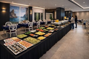 Disposição de buffet com diversos alimentos e um mural paisagístico ao fundo.