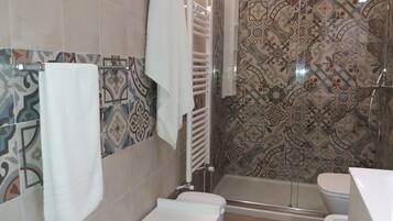 Casa de banho com chuveiro, sanita e lavatório.