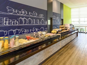 Um buffet de café da manhã com diversos alimentos e uma parede com ilustrações de xícaras de café.
