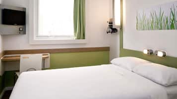 Quarto de hotel com cama, escrivaninha, televisão e um quadro na parede.