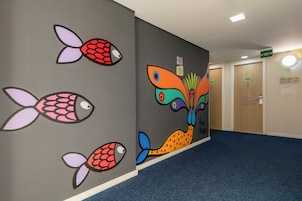 Um corredor com arte de parede de peixes coloridos, carpete azul e portas com as indicações 862 e 863.