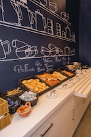 Uma área de buffet com diversos alimentos e um quadro-negro exibindo opções de café da manhã.