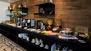 Disposição de buffet com diversos alimentos, uma máquina de café e um dispensador de chá.