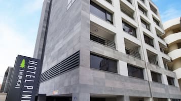 Um edifício moderno de hotel com vários andares, uma garagem e uma placa indicando que é um hotel.
