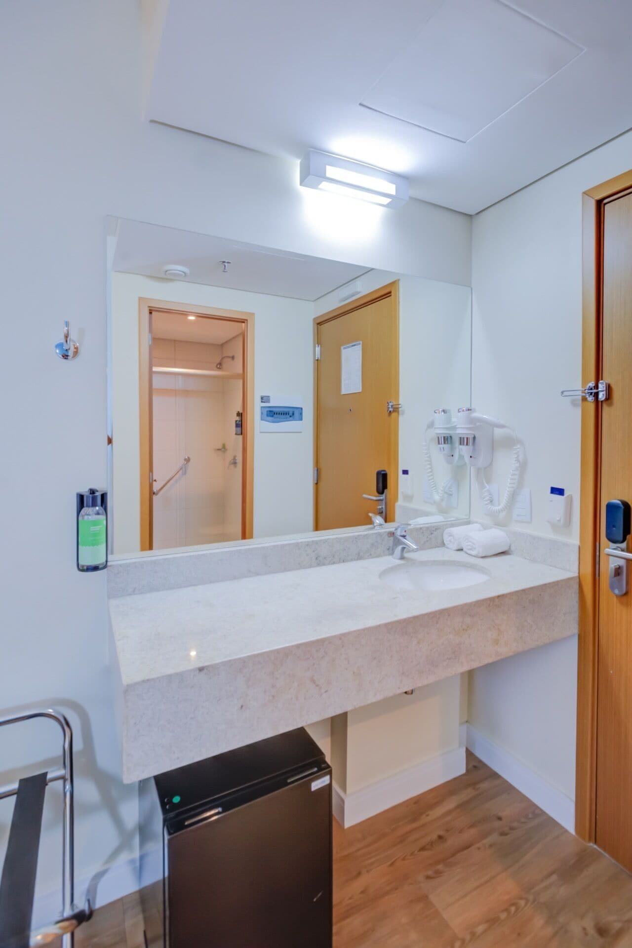 Casa de banho moderna com um espelho grande, lavatório e secador de cabelo.
