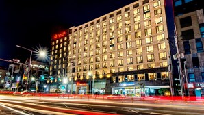 Um hotel com vários andares e uma placa de destaque com a inscrição 'RAMADA'.