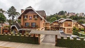 Um hotel com uma placa visível, entrada coberta e área de estacionamento.