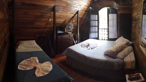 Quarto de cabana de madeira com duas camas, uma escrivaninha e um espelho.