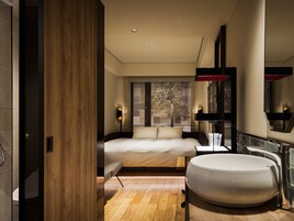 Quarto moderno com uma cama grande, uma banheira redonda e piso de madeira.