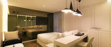 Quarto de hotel moderno com cama, escrivaninha, cadeira e televisão.