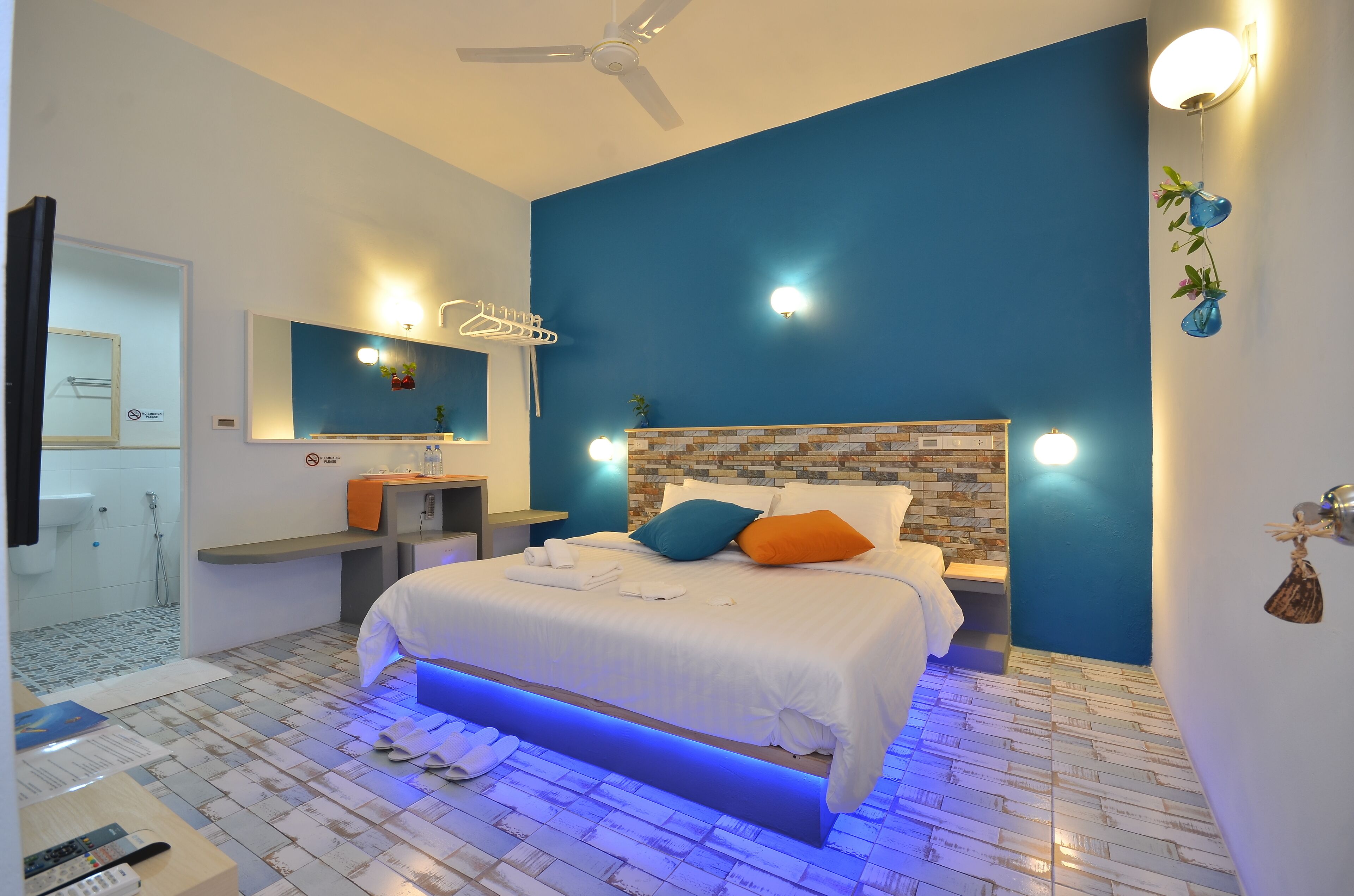 Quarto moderno com cama grande, mesa de cabeceira, espelho e banheiro visível por uma porta aberta.