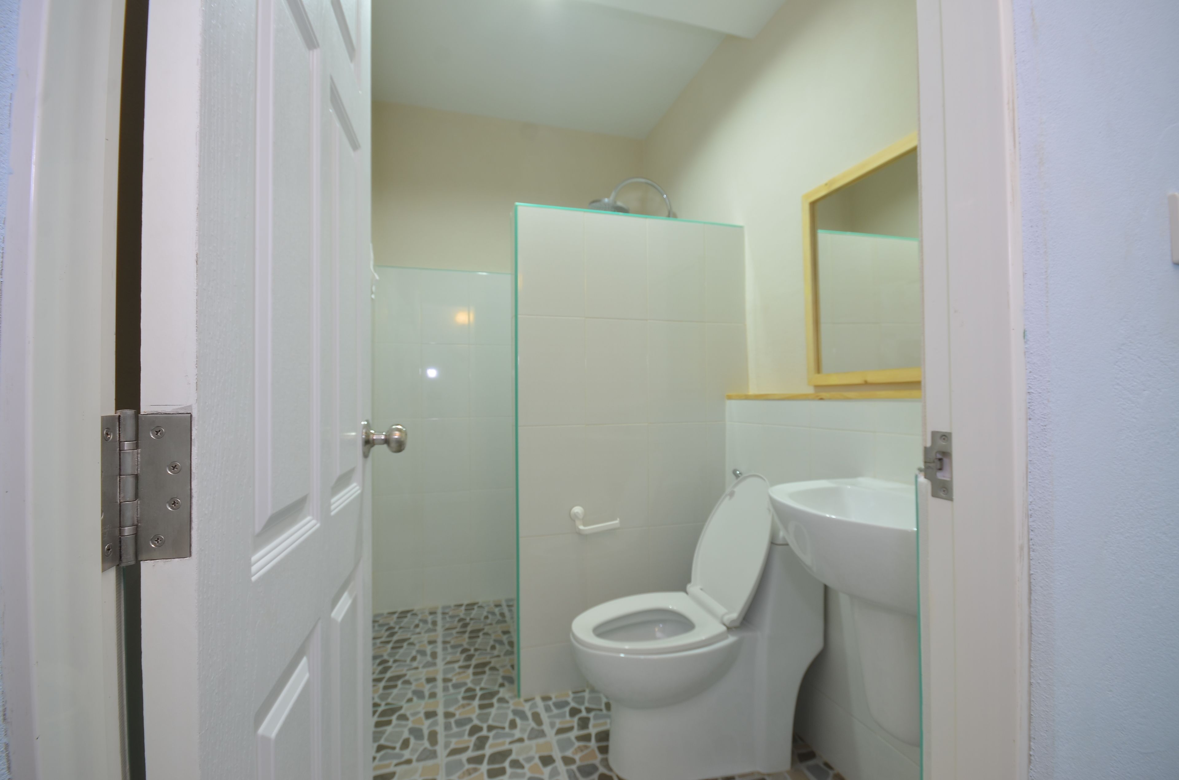 Casa de banho com sanita, cabine de duche em vidro e lavatório.